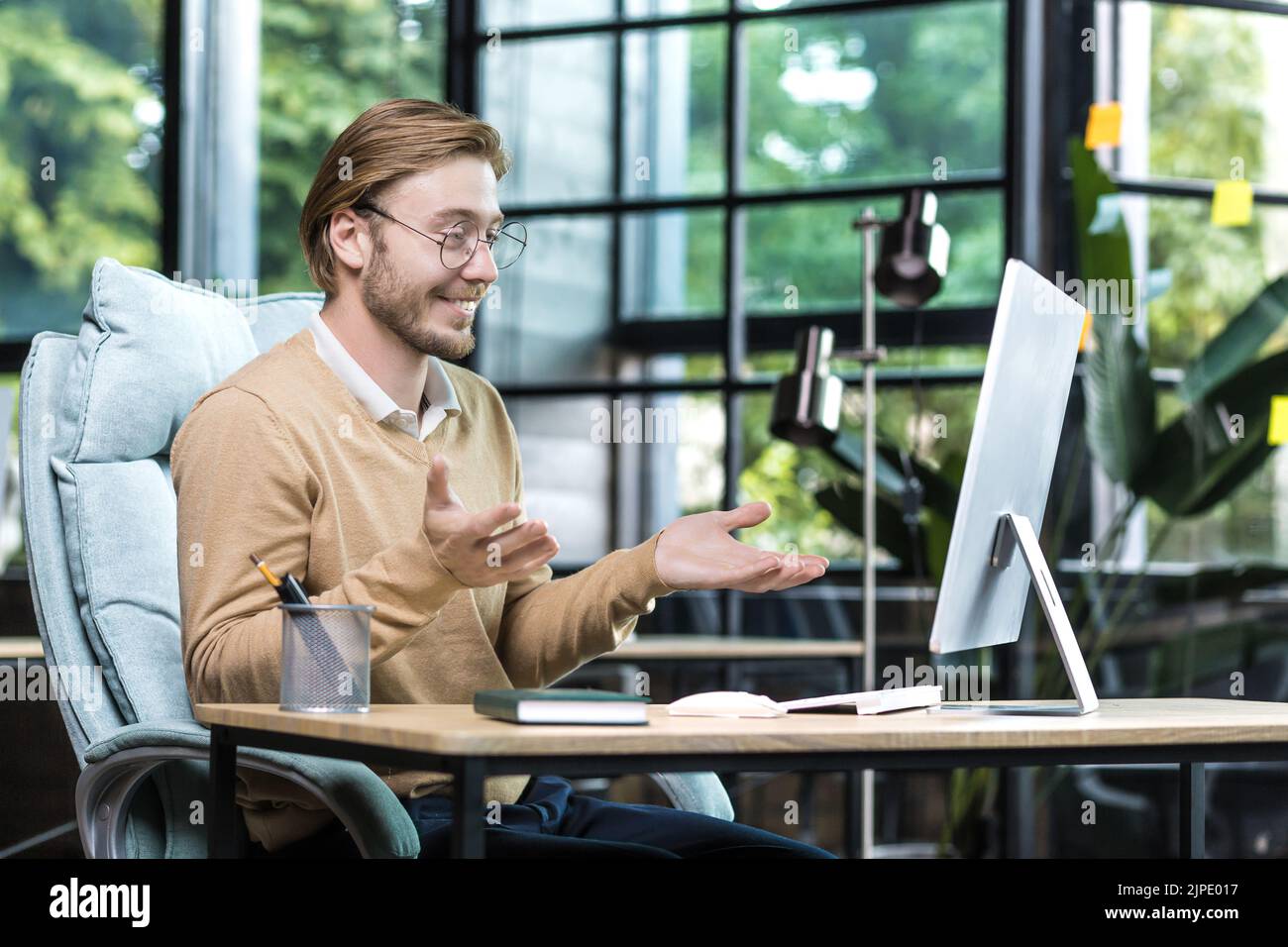 Happy and successful man at work looking at computer web camera smiling ...