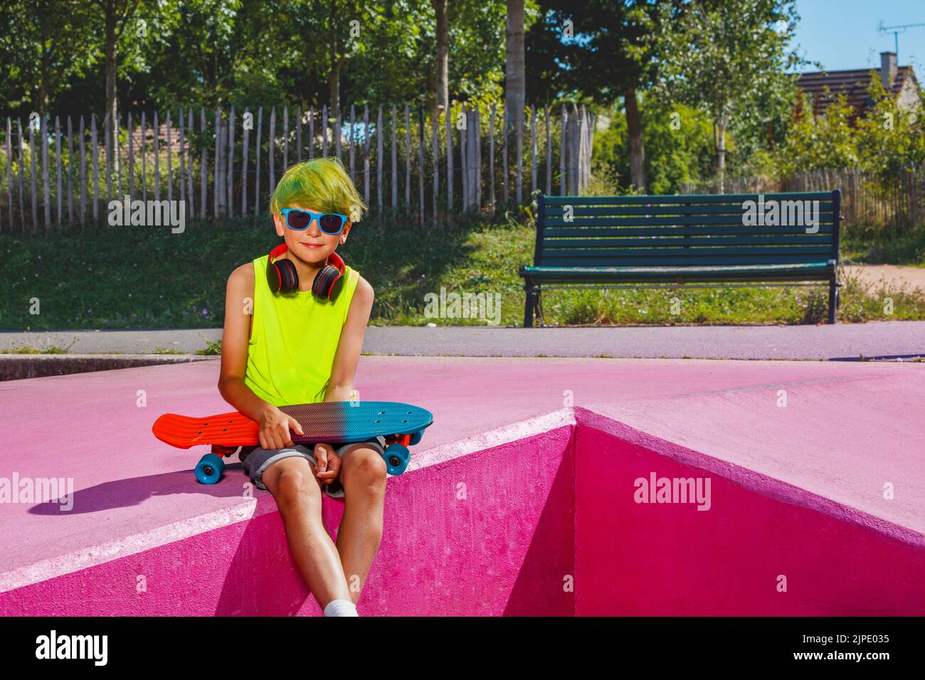 Child with green hair and skateboard sit on ramp, low angle view Stock ...