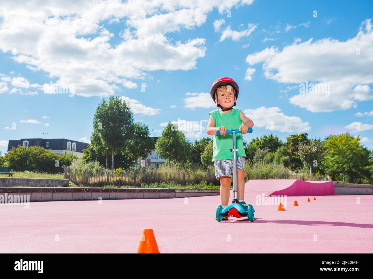 Boy on the kick scooter ride around orange cones at skate park Stock ...