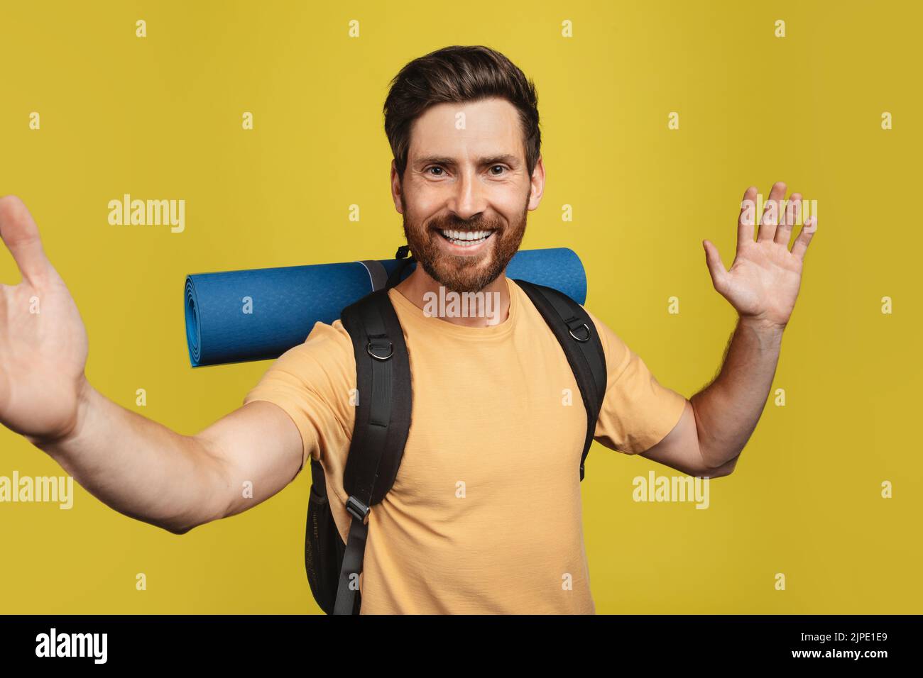 Happy middle aged man with camping gears taking selfie and waving to smartphone camera over ...