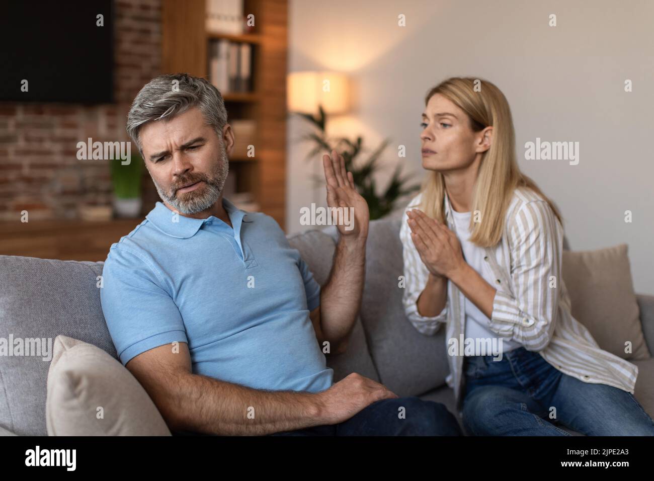 Adult caucasian wife asks and prays with gesture at sad husband with ...