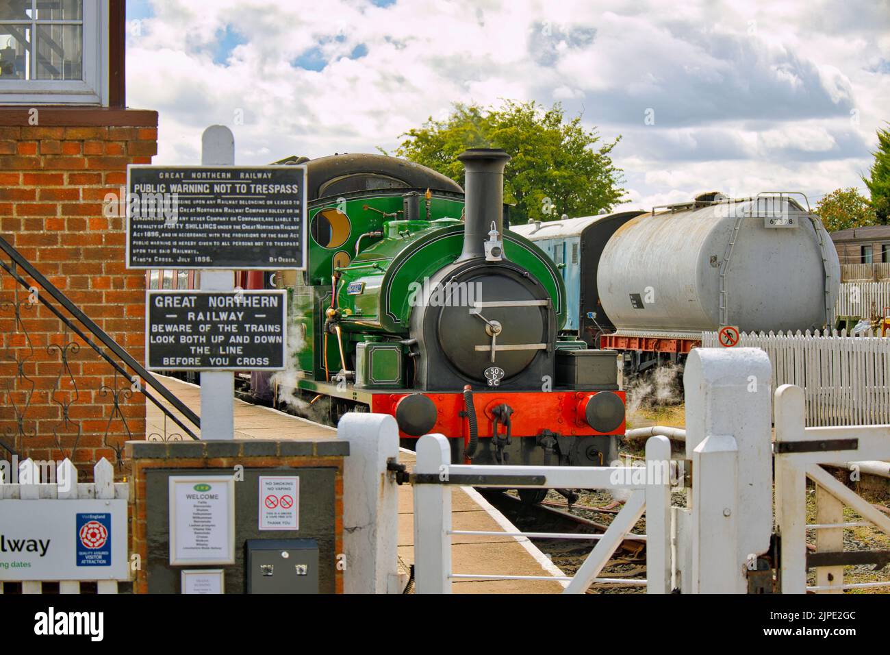 Steam train at platform viewed across signs in railway station at ...
