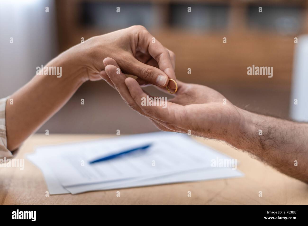 Hand of adult caucasian female gives ring to her ex husband at table ...