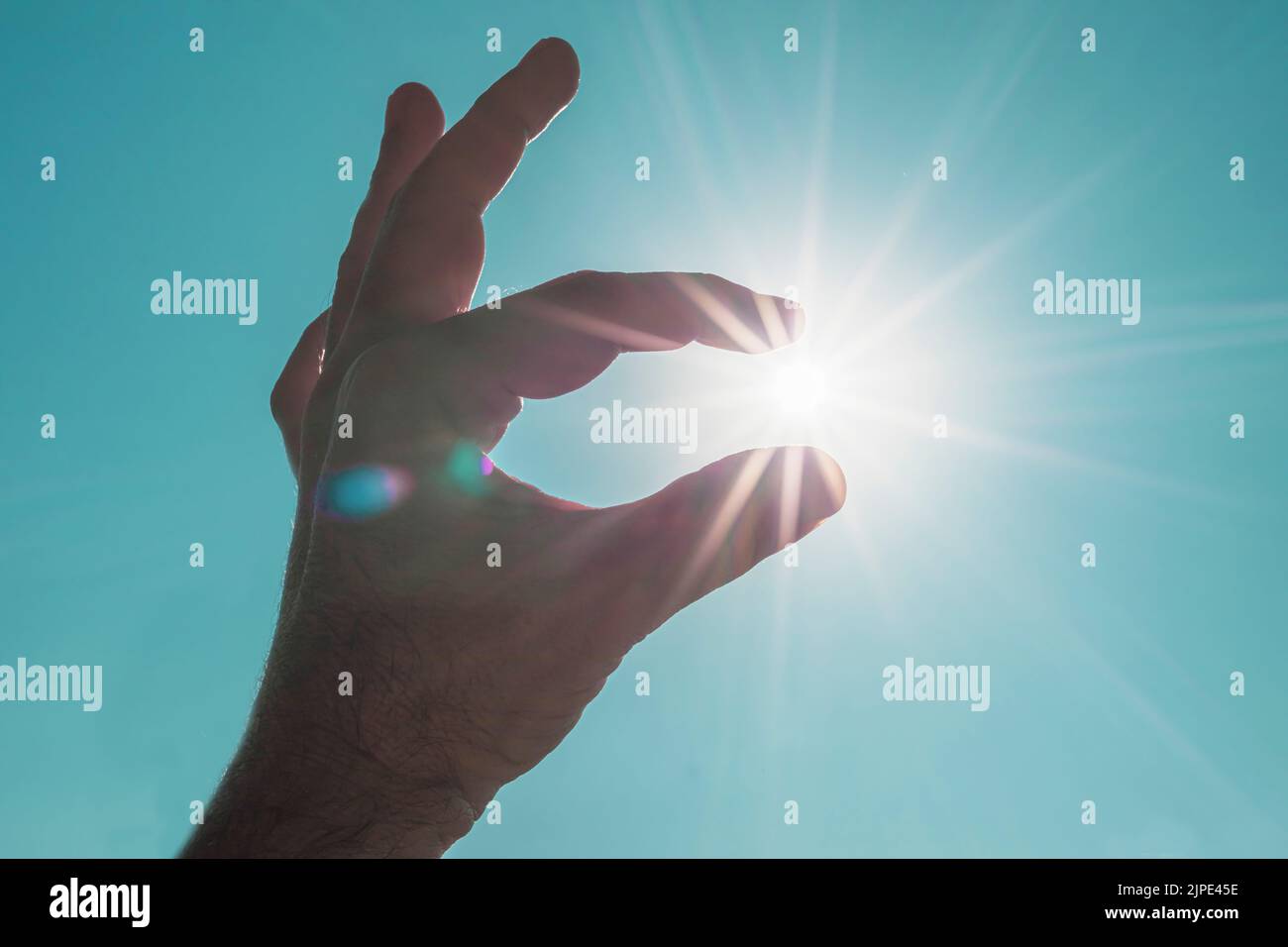 Hand of an adult man making an ok gesture over the blue sky and between ...