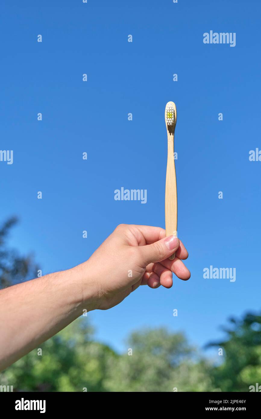 Hand holding an ecological toothbrush made of bamboo outdoors. Concepts ...