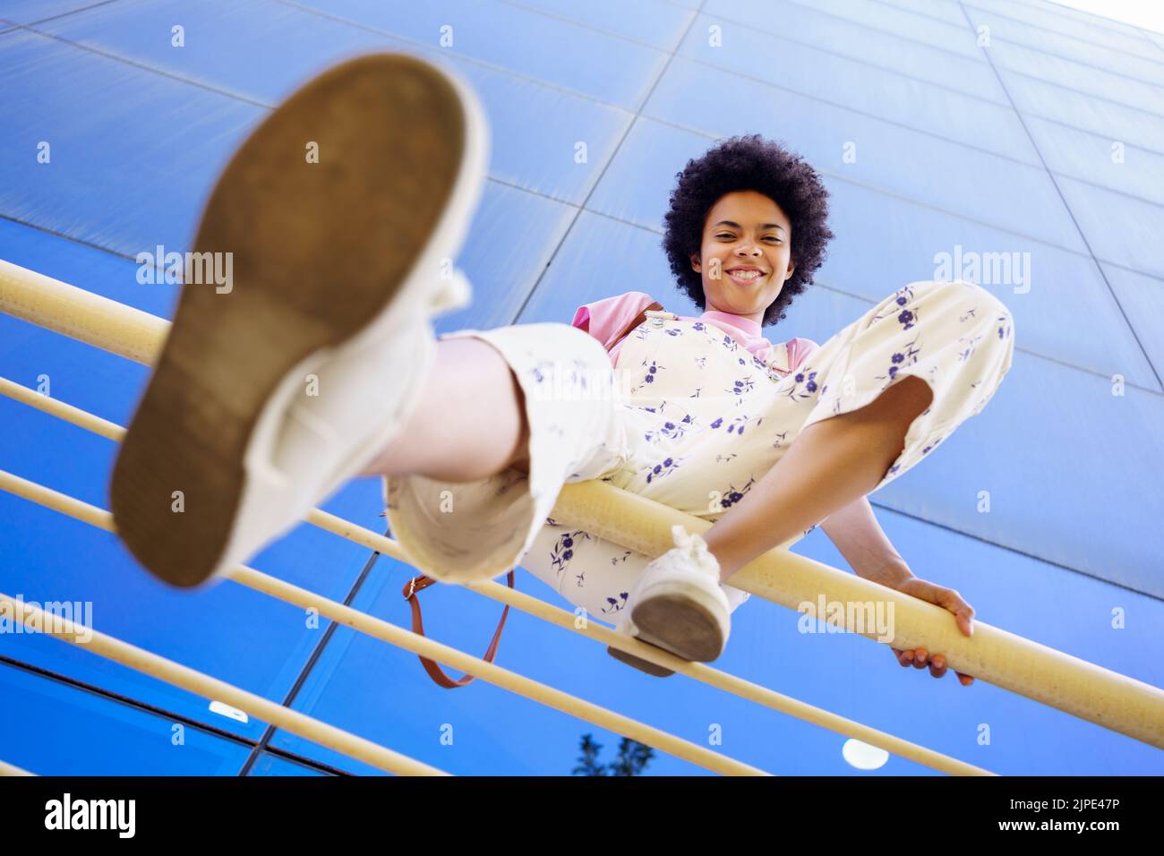 Smiling black woman sitting on railing Stock Photo - Alamy