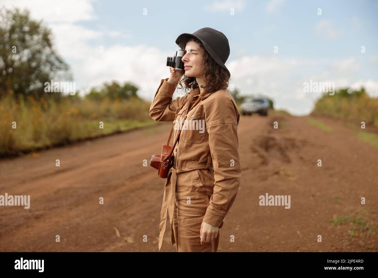 Pretty lady taking photo while standing on the road in savannah Stock Photo - Alamy
