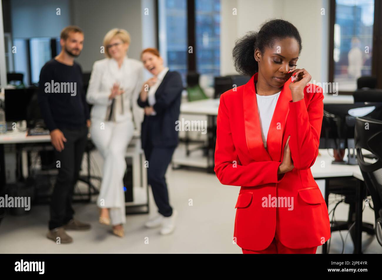 Young african woman crying because of the ridicule of colleagues ...