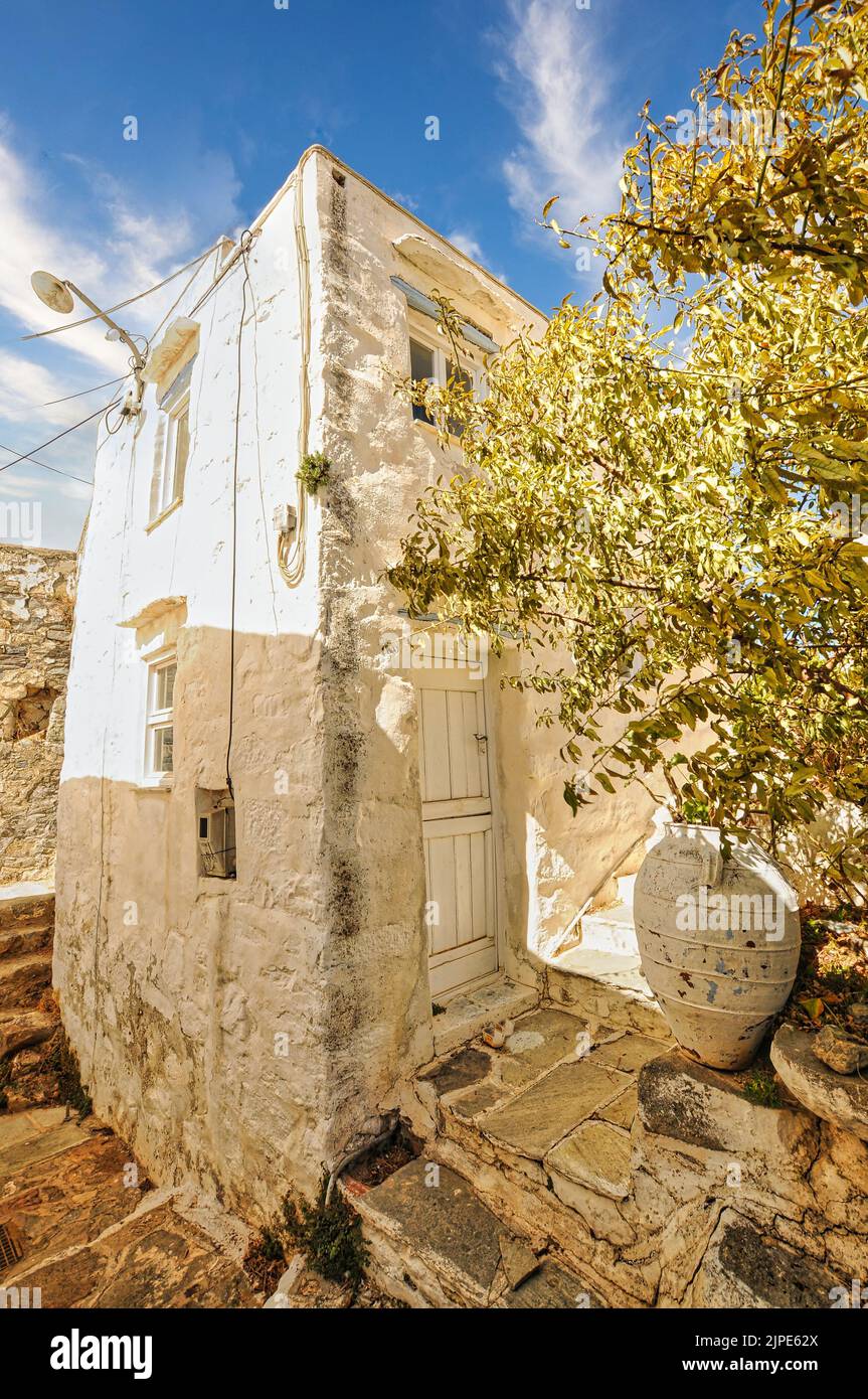 A vertical shot of a traditional whitewashed house and stone paved ...