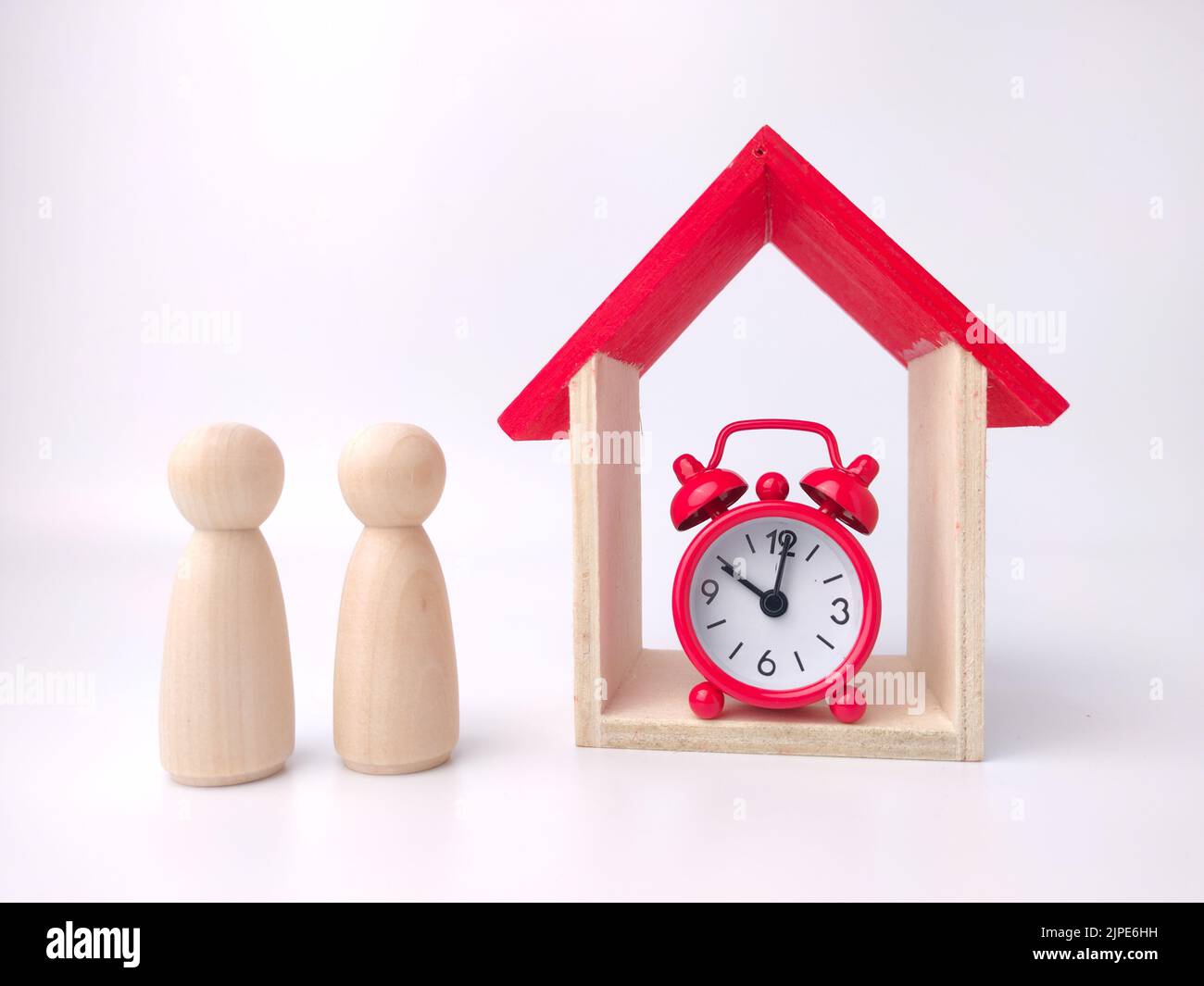 Wooden doll figures of a couple, an alarm clock and a toy house on a ...