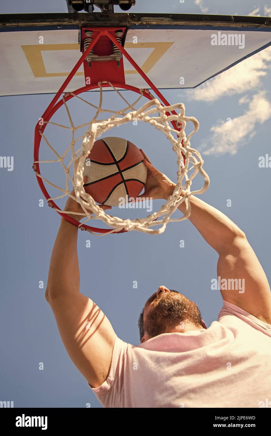 man dunking basketball ball through net ring with hands, sport success ...