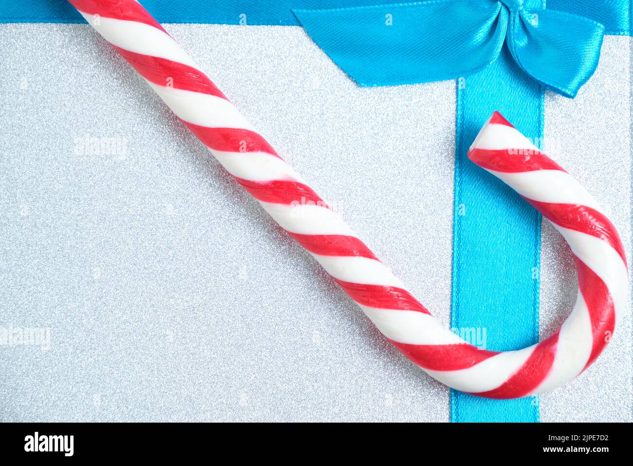 Christmas gift box with blue bow and a red and white candy shape of ...