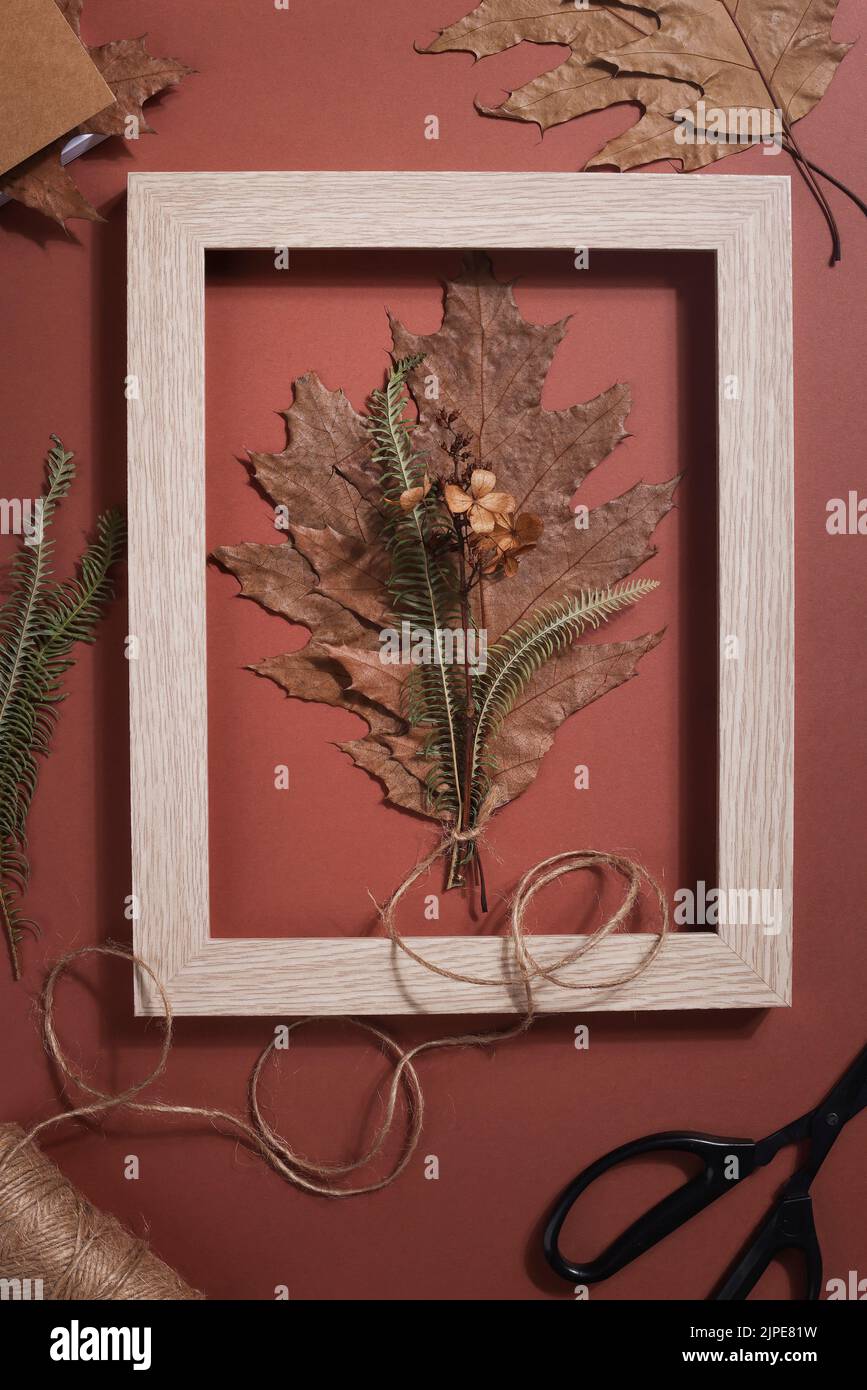 bouquet from dried pressed leaf in frame with scissors, rope and ...