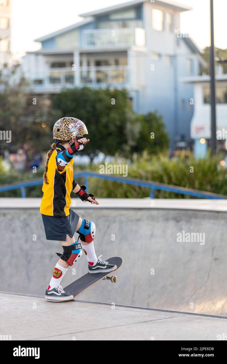 A vertical shot of a kid wearing a helmet doing tricks on a skateboard ...