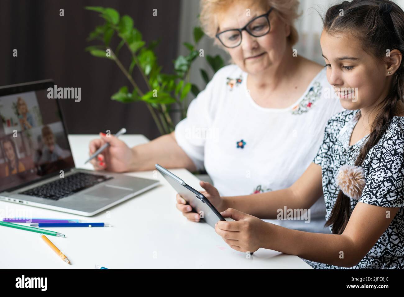 Older woman grandma and little girl grandkid with homework remote study ...