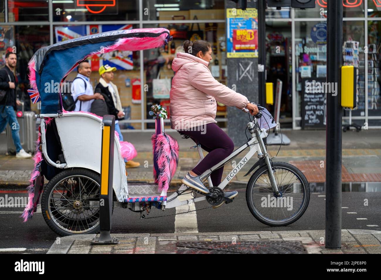LONDON - May 20, 2022: Woman wearing pink coat while riding rickshaw on ...