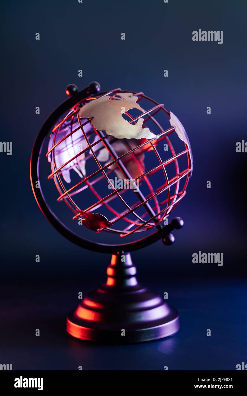 Close up metallic model of a globe with map in blue and red neon light ...