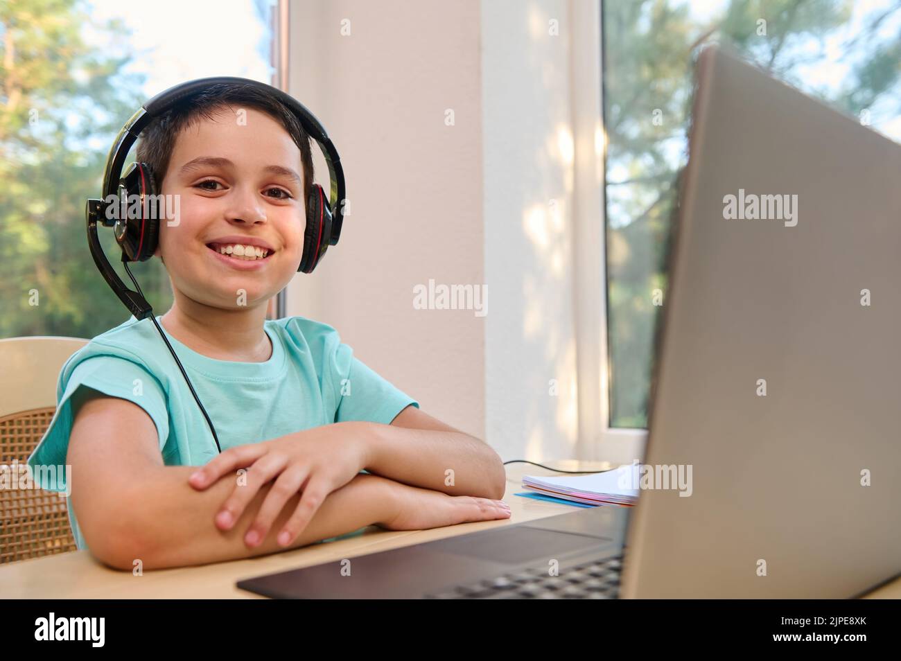 Adorable, smart student of an online school, in headphones, smiles at ...
