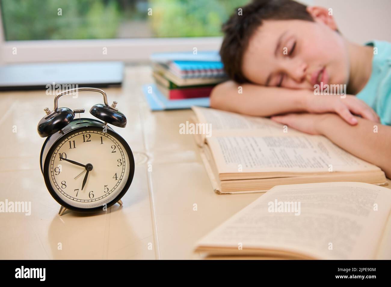 Soft focus on a black alarm clock on the blurred background of a tired ...