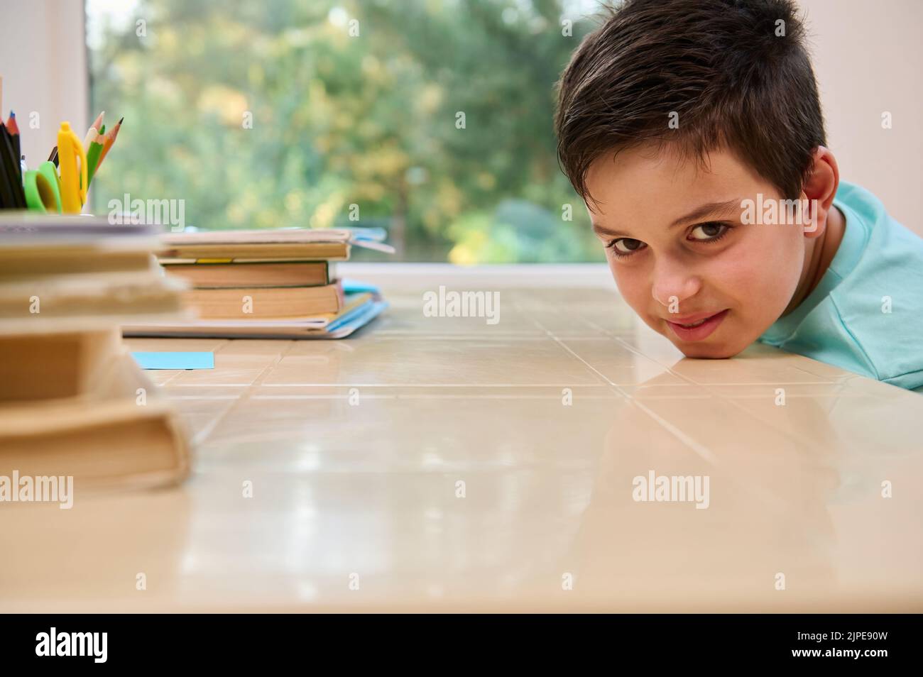 Adorable teenage schoolboy cutely smiles at camera, feels happy to ...