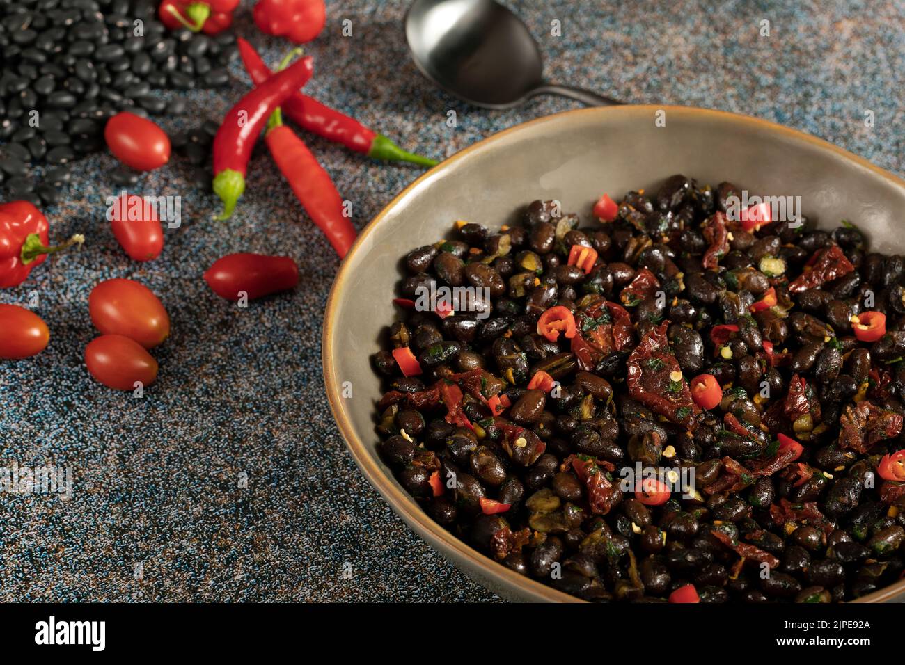 Black beans with dried tomatoes and red Cayenne chili peppers in a ...