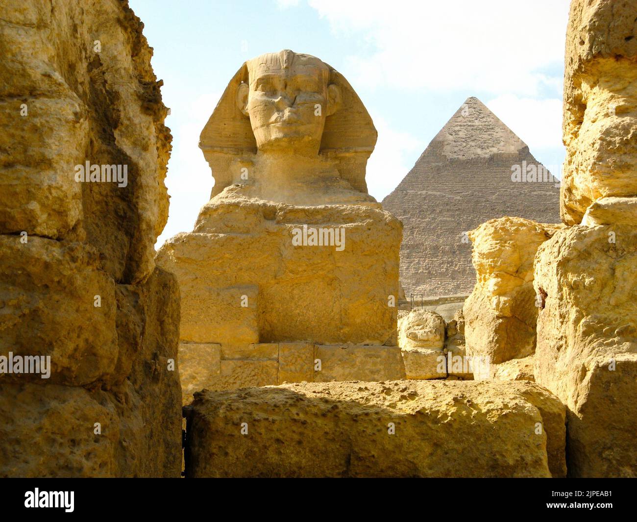 A closeup shot of the Sphinx from behind old rocks and the Great ...