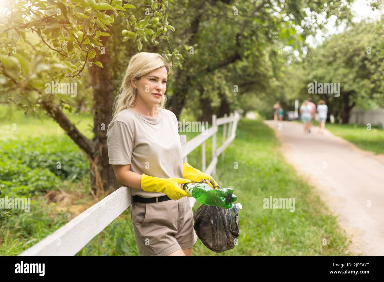 Young beautiful volunteer picking up litter in park Stock Photo - Alamy