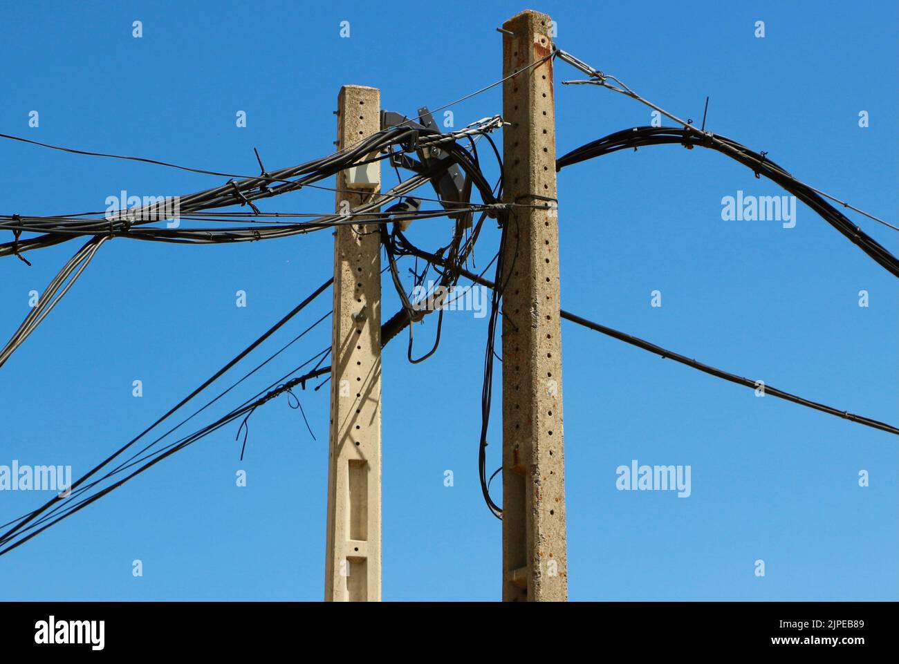 Tangled electric power cables on concrete posts in the street in ...