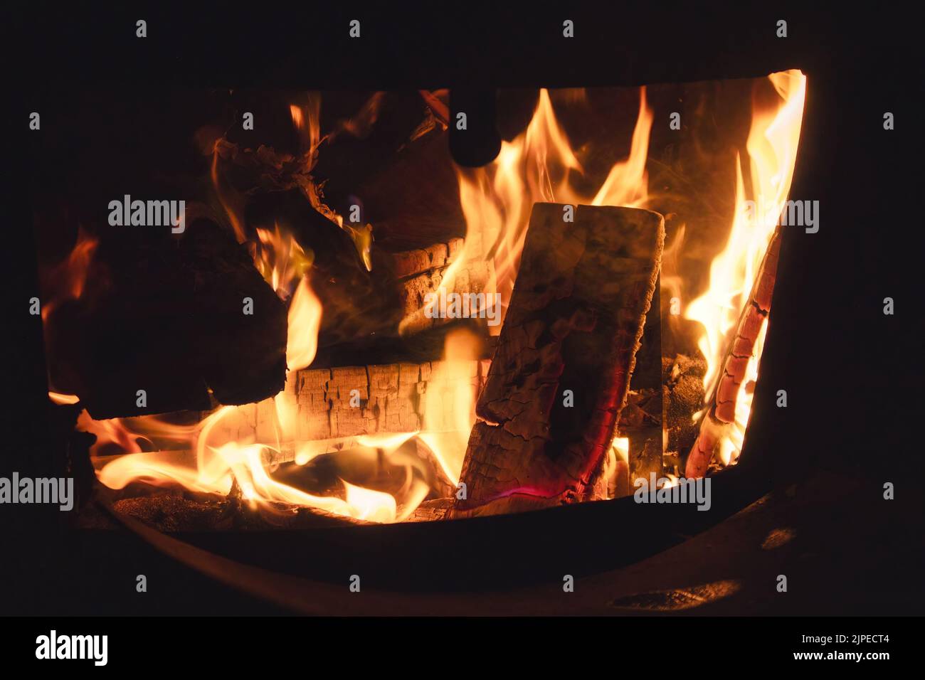 Close-up of pieces of wood burning in an iron stove to cook for ...