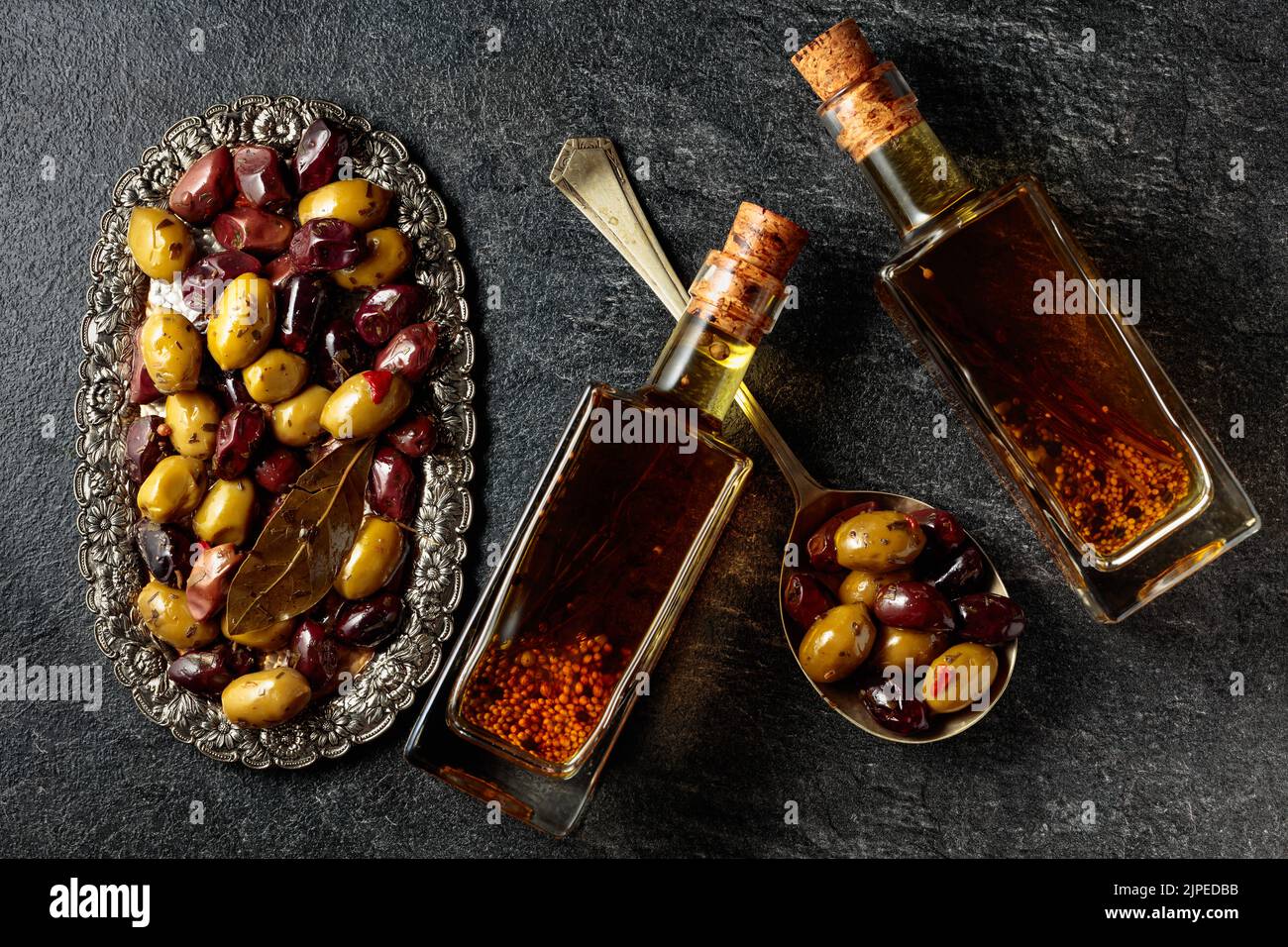 Spicy olives and olive oil on a black stone table. Top view Stock Photo ...