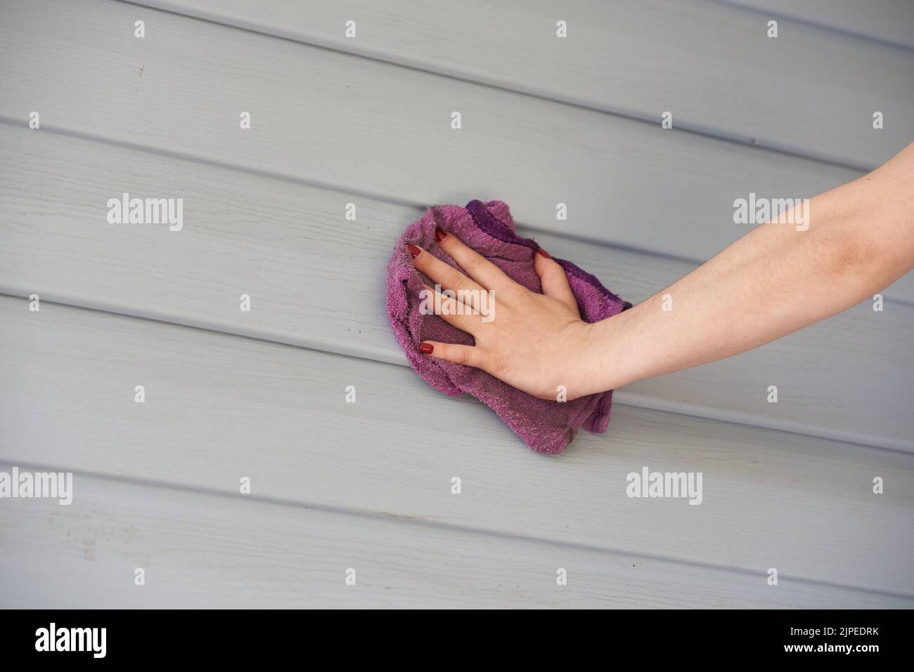 Female hand cleaning the exterior walls of a house made of plastic ...