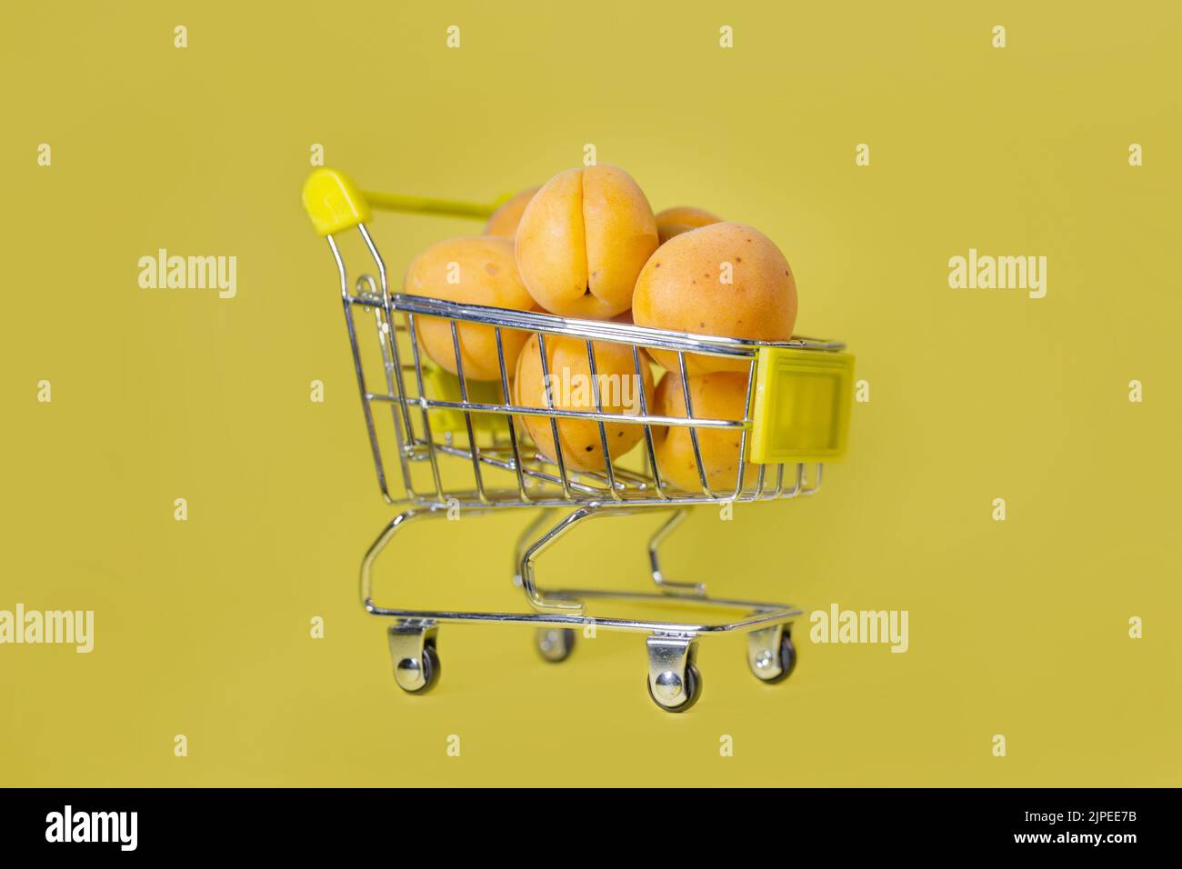 apricots in a small shopping cart on a yellow background Stock Photo ...