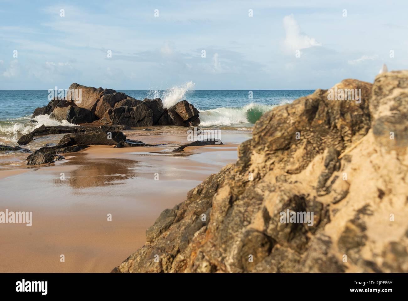 A wave breaks about a rock during a curtain on the sea. Farol da Barra ...