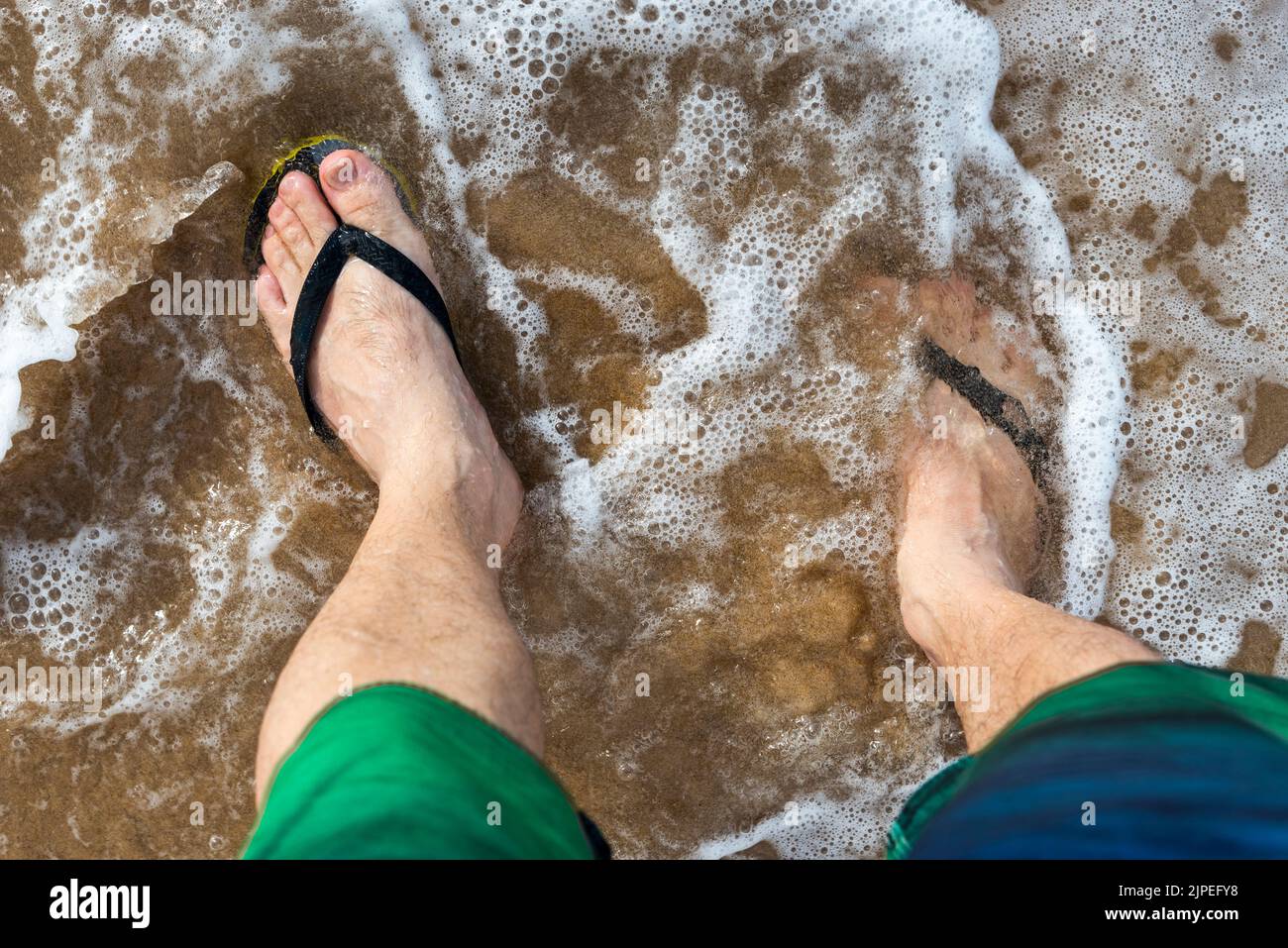 Top to bottom view of feet on the beach sand. Barra beach lighthouse ...