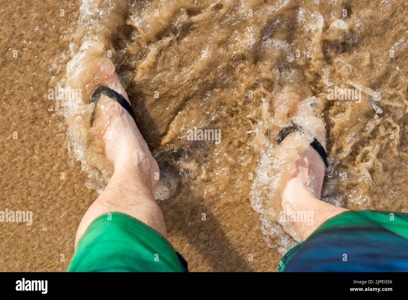 Top to bottom view of feet on the beach sand. Barra beach lighthouse ...