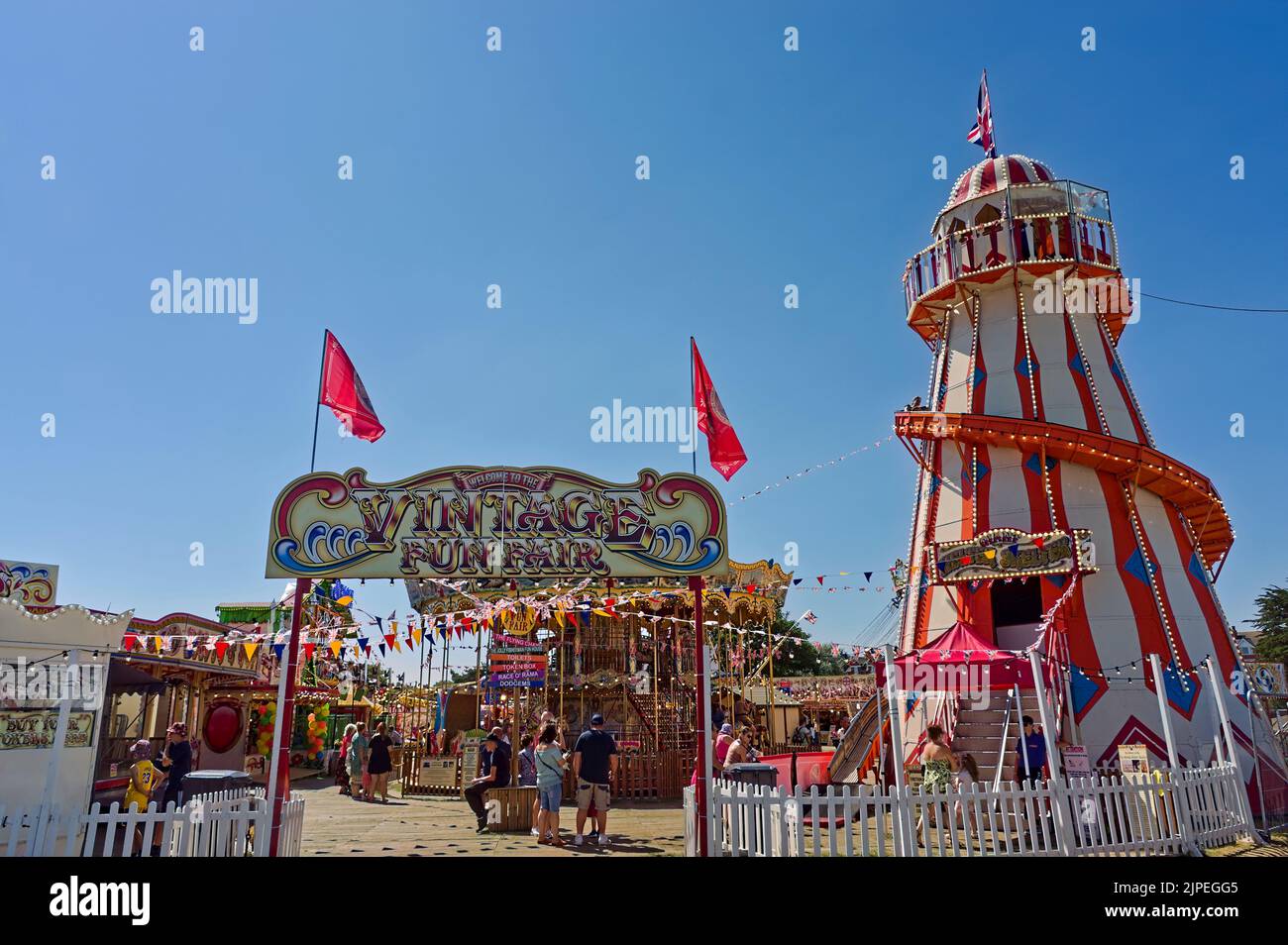 Vintage fun fair entrance with people enjoying the fairground on a hot ...
