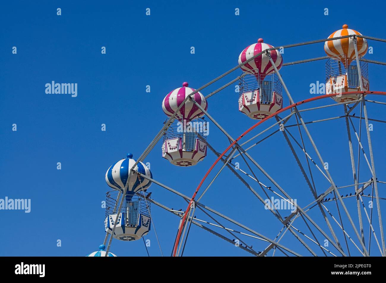 Close-up of the pods on a Ferris wheel fair ride against a blue sky in ...