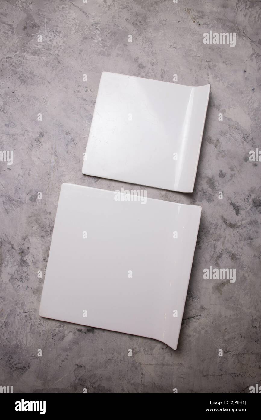 white ceramic square plates on a concrete background Stock Photo - Alamy