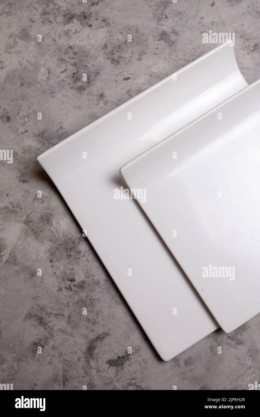 white ceramic square plates on a concrete background Stock Photo - Alamy