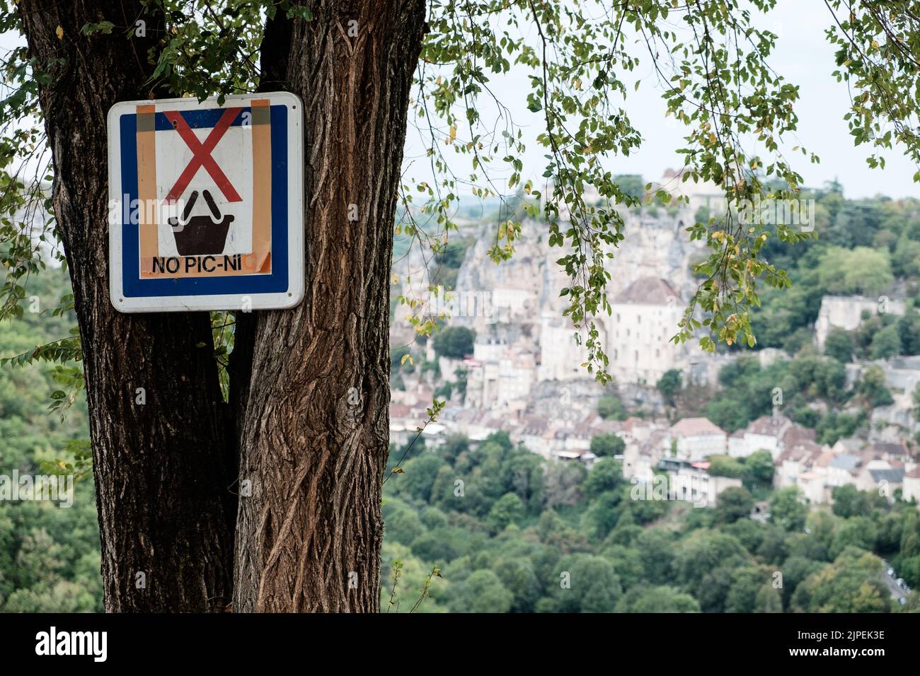 No picnic sign on a tree with Rocamadour clifftop village in the ...