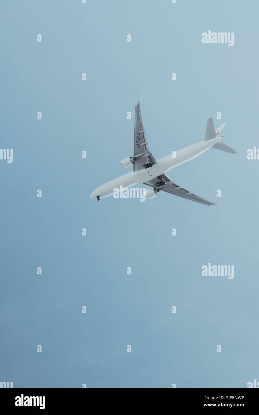 A vertical shot of an airplane soaring above Tokyo Stock Photo - Alamy