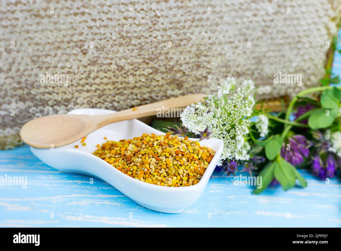 raw organic bee pollen on a wooden board surrounded by wildflowers ...