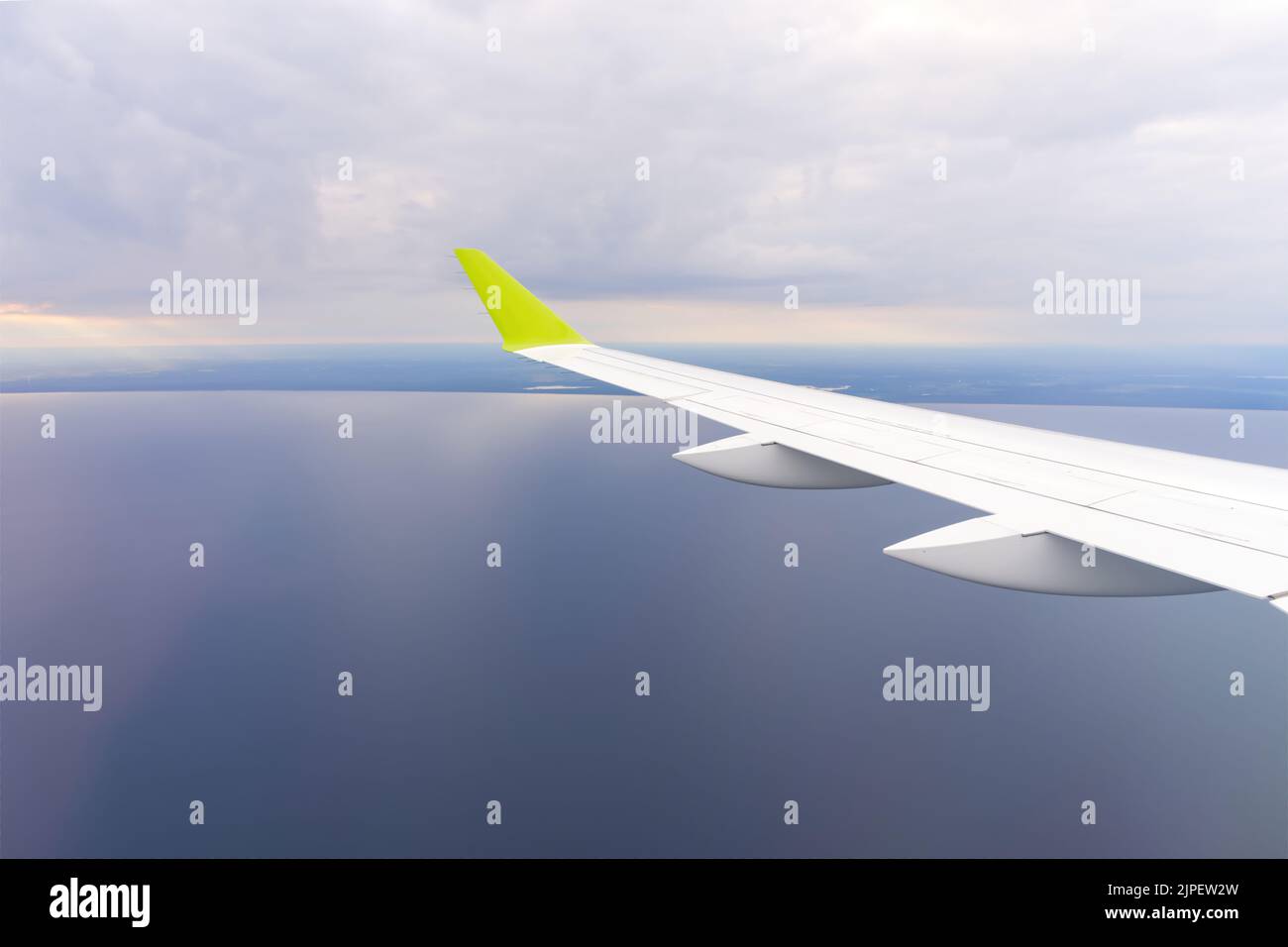 Wing of an airborne airplane ocean below. the plane flies over the ...