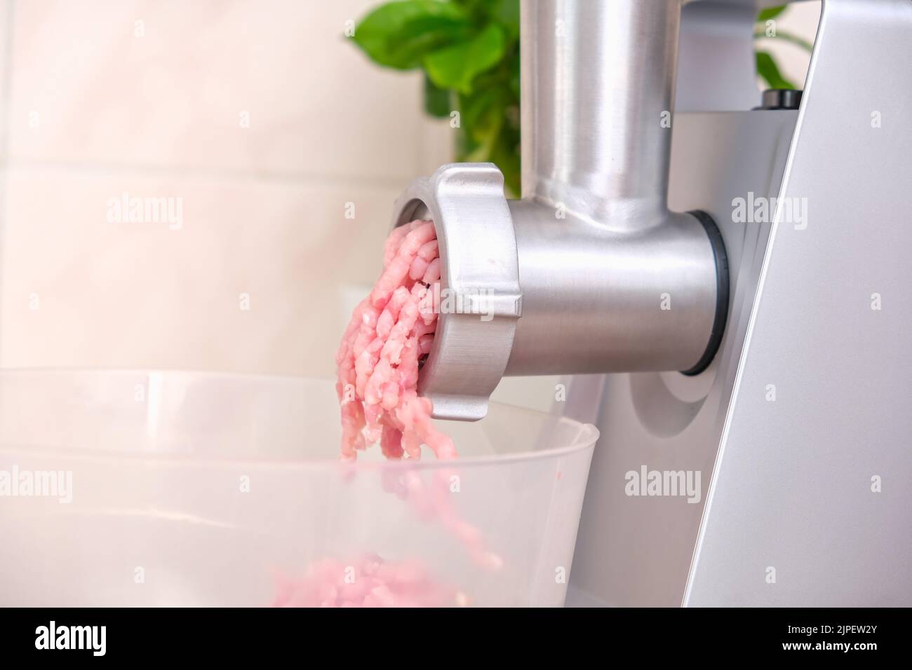 A man processes meat in an electric meat grinder. Preparation of minced ...