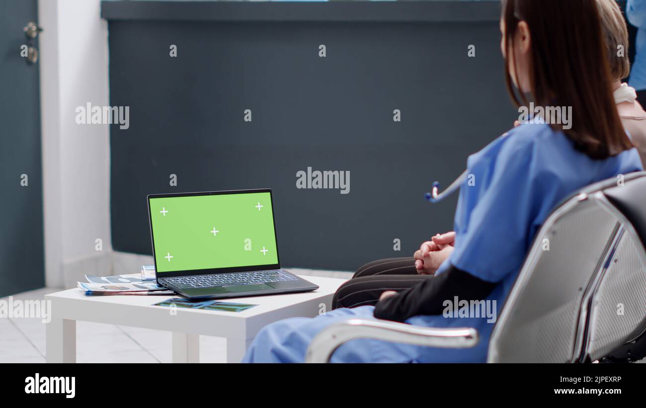 Asian nurse and patient looking at laptop with greenscreen on display ...