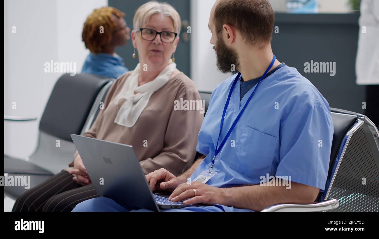 Medical assistant working on laptop to give diagnosis to old patient ...