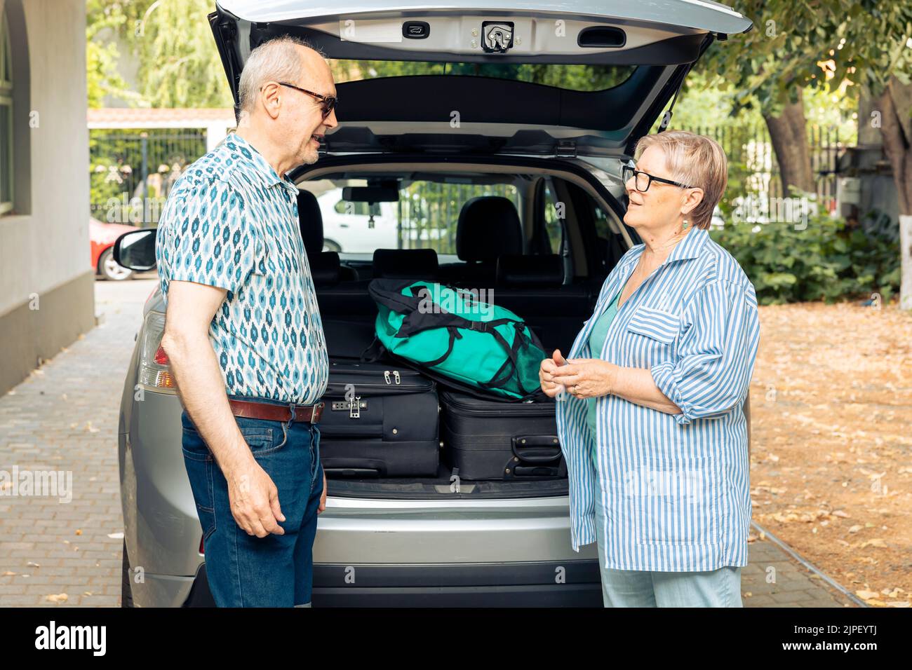 Retired people travelling on vacation by car, talking about urban ...