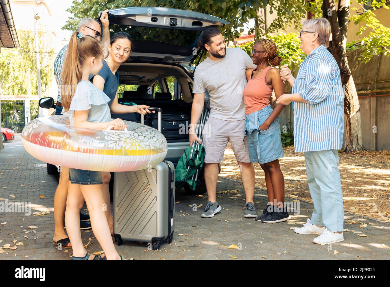 Diverse family and friends travelling on holiday, preparing to leave on ...