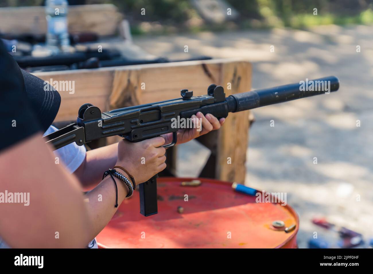 Unrecognizable young person holding uzi gun training on shooting range ...