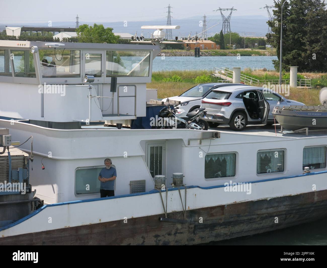 A cargo boat transporting goods on the River Rhone also has two cars on ...